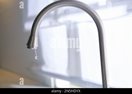 Water drop falling down from tap on blurred background, closeup Stock ...