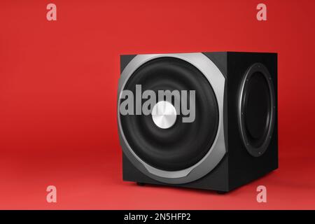 Modern subwoofer on red background, closeup. Powerful audio speaker ...