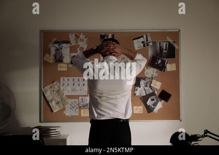 Detective looking at evidence board in office Stock Photo - Alamy