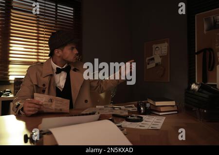 Old fashioned detective working at table in office, focus on hand with ...
