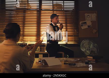 Old fashioned detective working with client in office Stock Photo - Alamy