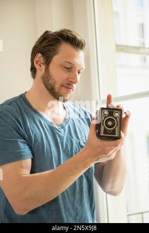 Man examining pinhole camera at window, Munich, Bavaria, Germany Stock ...