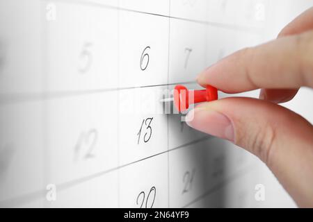 Woman pinning Friday 13th on calendar, closeup. Bad luck superstition ...