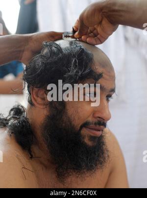 A Muslim pilgrim has his head ritually shaved after he cast stones at a ...