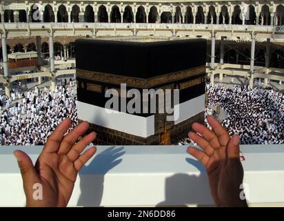 A Muslim pilgrim prays in front of the Kaaba, the cubic building at the ...