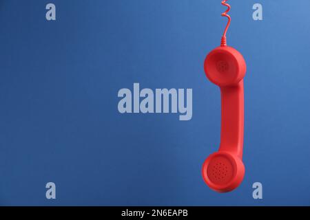 Red corded telephone handset hanging on white background. Hotline ...