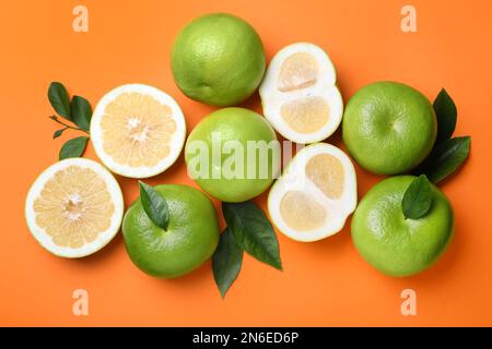 Fresh ripe sweeties and green leaves on orange background, flat lay ...
