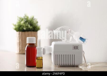 Modern nebulizer with face mask and medications on white background ...