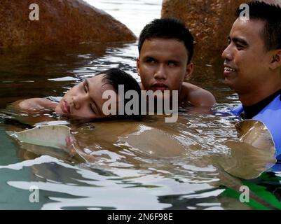 Filipino disabled children are helped by trainers to touch and feel a ...