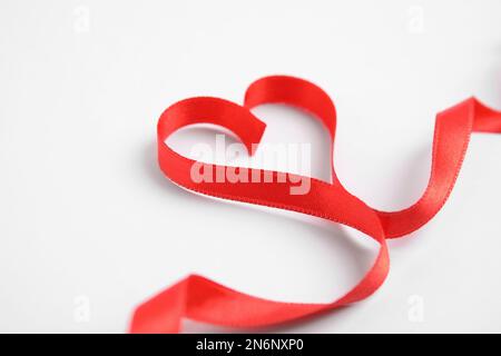 Heart made of red satin ribbon on pink background. Valentine's Day ...