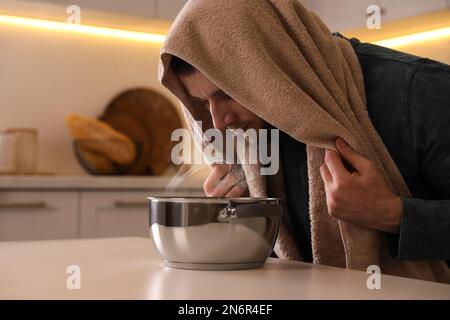 Man taking treatments at table indoors. Steam inhalation Stock Photo ...