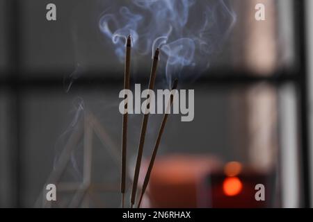 Incense sticks smoldering on blurred background, closeup. Space for ...