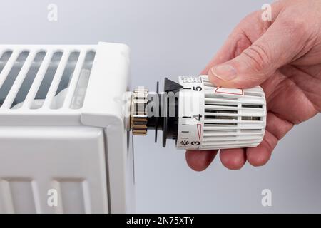 Man hand with glove increases room temperature on radiator thermostat ...