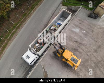Waste loading operation, loader dumping trash in a truck on a site for ...