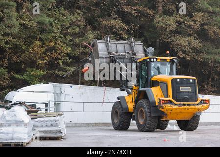 Waste loading operation, loader dumping trash in a truck on a site for ...