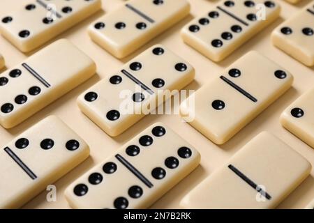 Classic domino tiles on beige background, flat lay. Space for text ...