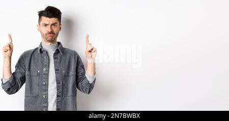 Confused funny guy with moustache pointing fingers up at something ...