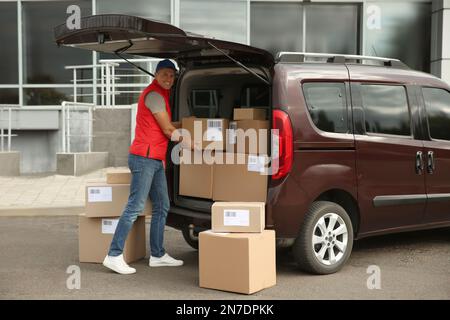 Courier loading packages in car trunk outdoors Stock Photo - Alamy
