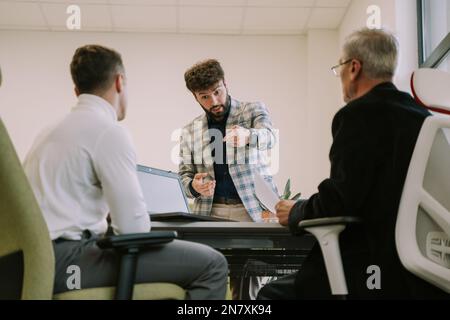 Disappointed and angry boss overlooking and correcting his employees at ...