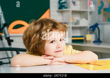 Back to school! Happy cute industrious child is sitting at a desk ...
