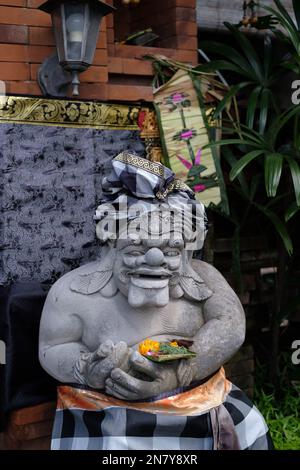 The gate guard statue is made of stone covered by Balinese sacred cloth ...
