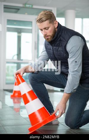 man putting safety cone on tiled floor Stock Photo - Alamy