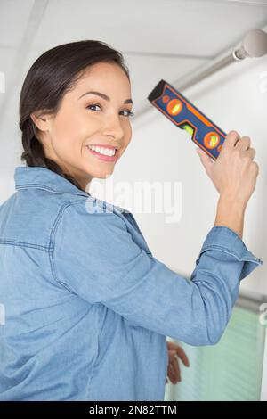 woman checking curtain rail with a spirit level Stock Photo - Alamy