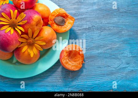 Ripe apricots decorated with yellow flowers on a plate on a wooden ...