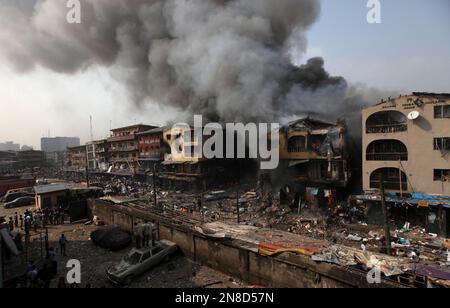 Residents look as a fire burns out residential homes and a warehouse on ...