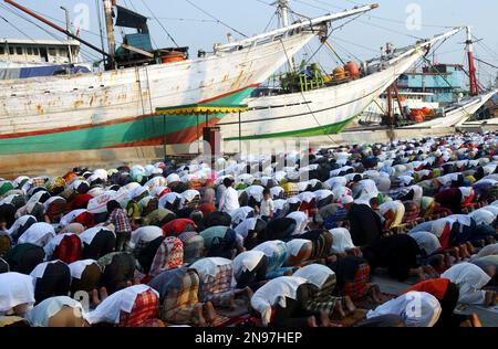 Muslim men, bowing toward Mecca, prepare to perform Eid al-Fitr prayers ...