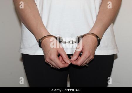 Arrested female with hands cuffed standing against a wall Stock Photo ...