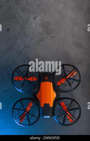 Orange quadcopter mini spy drone on a dark background with blue ...