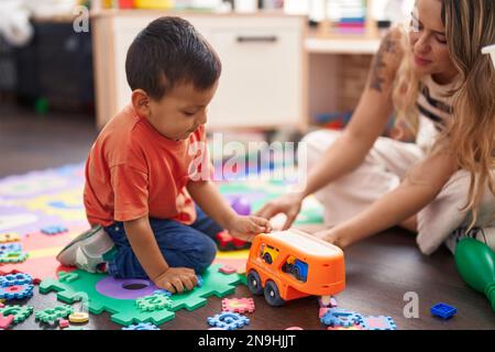 Teacher and toddler playing with cars toy sitting on table at ...