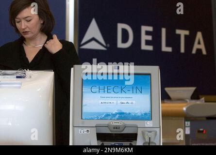 A passenger uses a Delta Airlines self-service check-in kiosk at the ...