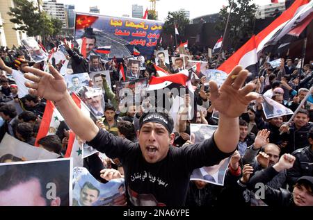 Syrian Baath Party supporters chant slogans, as they carry Syrian flags ...