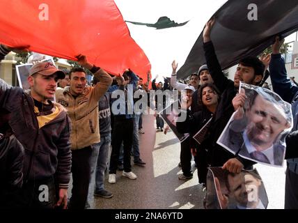 Syrian Baath Party supporters chant slogans, as they carry Syrian flags ...