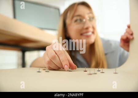 Young woman putting pins on chair while her colleague sitting down in ...