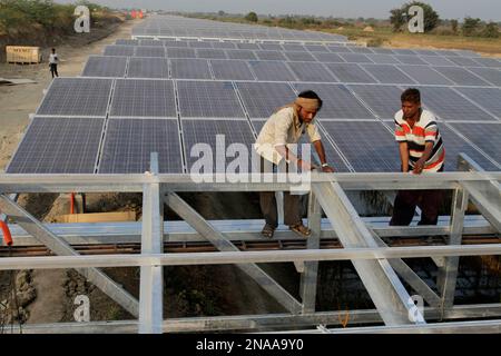 Indian laborers work amid installed solar panels atop the Narmada canal ...