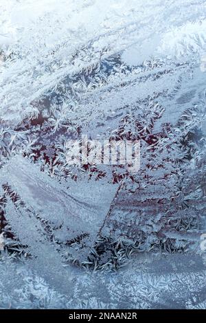 Frost patterns on a window against a vibrant orange sunrise or sunset ...