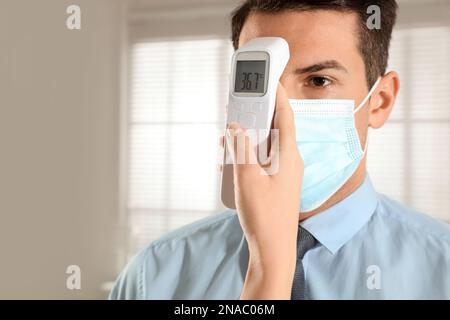 Measuring of man's temperature in office. Coronavirus epidemic Stock ...