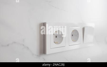 Group of white european electrical outlets with plug on gray concrete ...