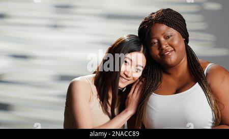 Fit women with diverse body shapes standing together in a studio ...