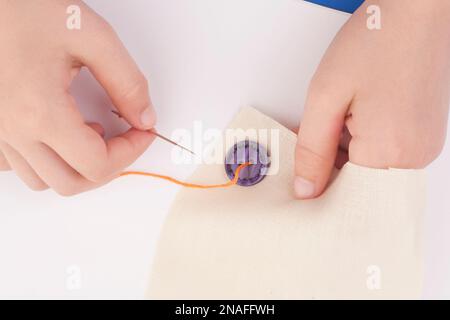 Child sewing on a button Stock Photo - Alamy