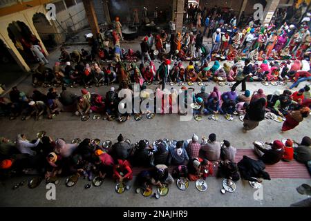 Sikh devotees eat a meal from a community kitchen at a gurudwara, or ...