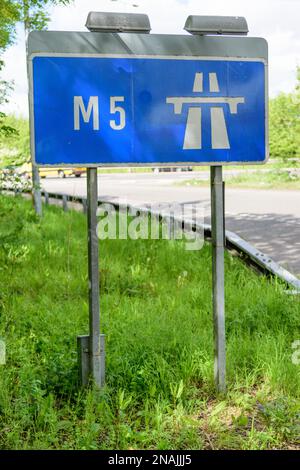 A blue street sign informs drivers the road they are driving on is the ...