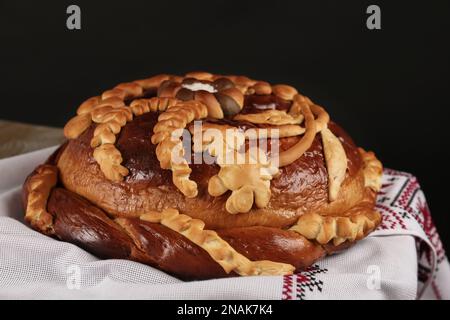 Rushnyk with korovai on table against black background, closeup ...
