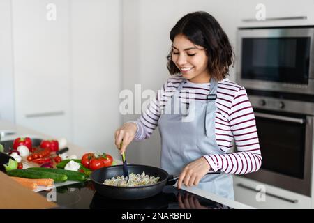 Beautiful woman frying rice with vegetables in kitchen Stock Photo - Alamy