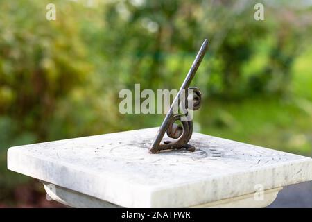 A vintage sundial with green patina throws a long shadow, tracking the ...