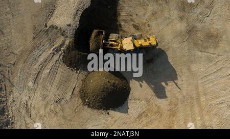 A front end loader machine tipping sand in a quarry Stock Photo - Alamy