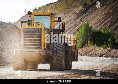 A front end loader machine tipping sand in a quarry Stock Photo - Alamy